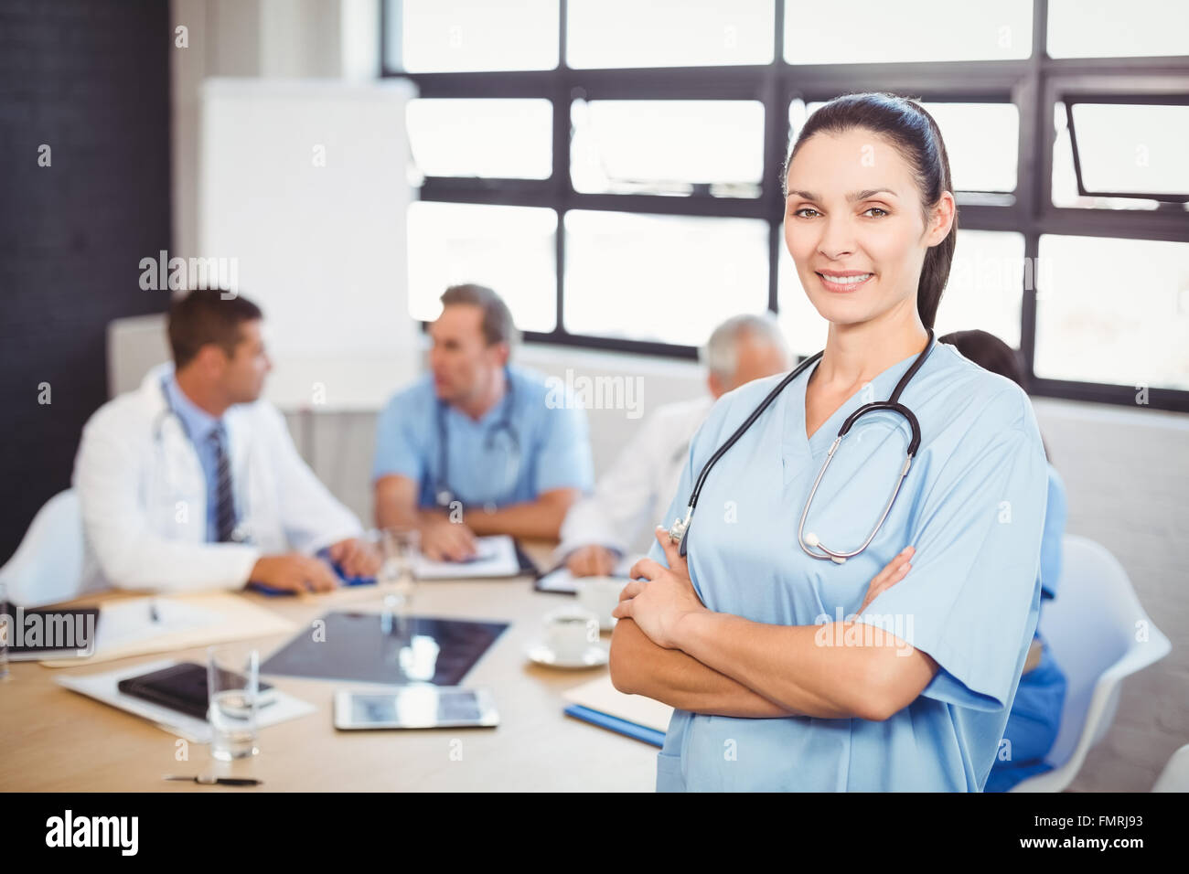 Happy female doctor standing with arms crossed in conference room Stock ...