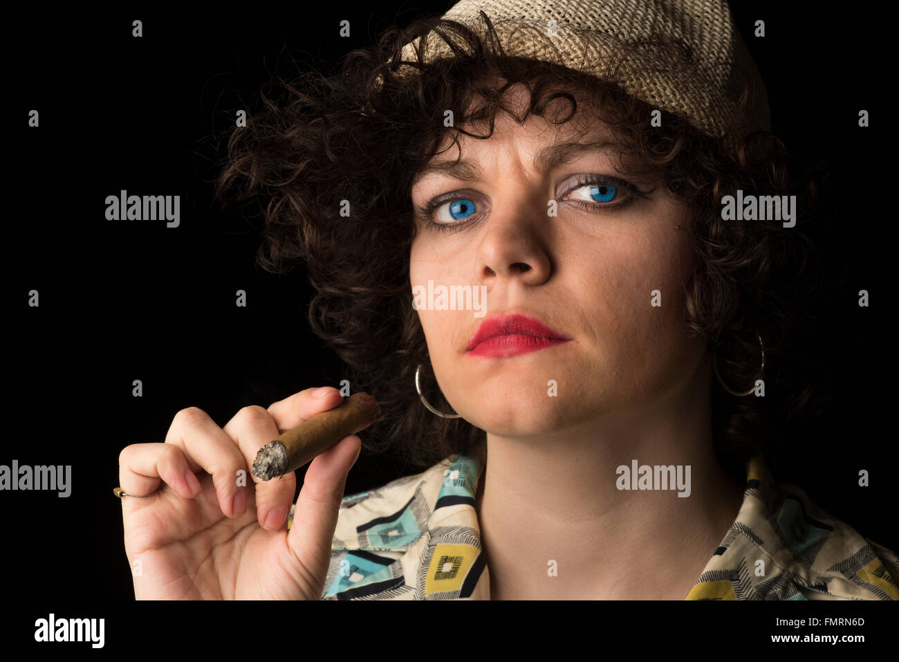 Pretty young Caucasian woman smoking cigar with intense look at camera ...