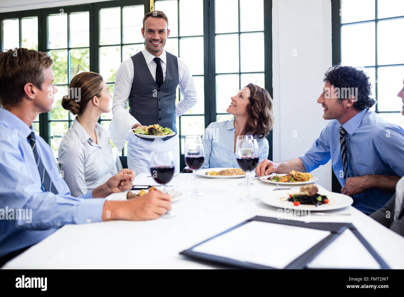 Waiter serving salad to business people Stock Photo - Alamy
