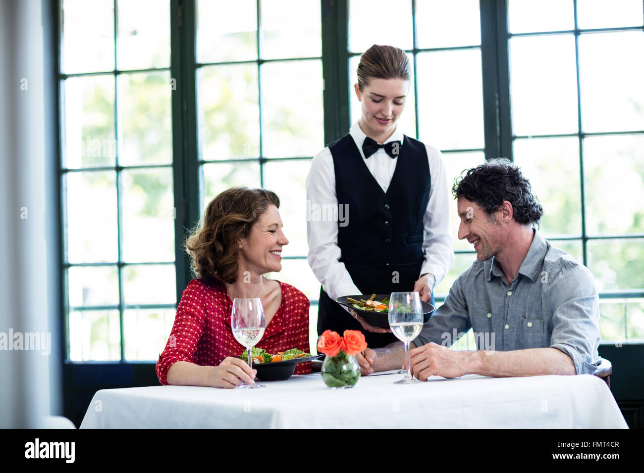 Waitress serving meal to a couple Stock Photo - Alamy