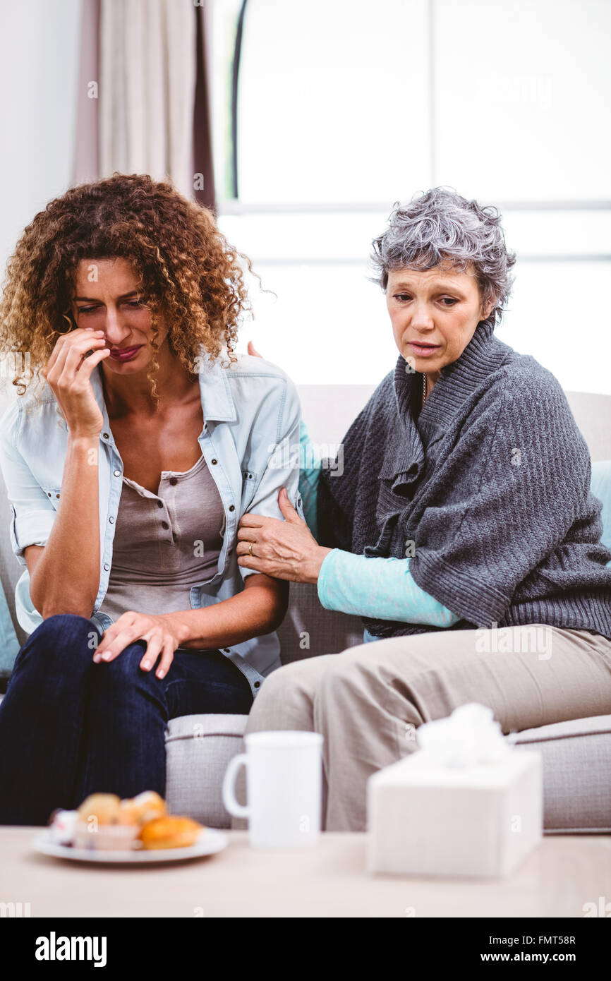 Mother comforting crying daughter sitting on sofa Stock Photo - Alamy