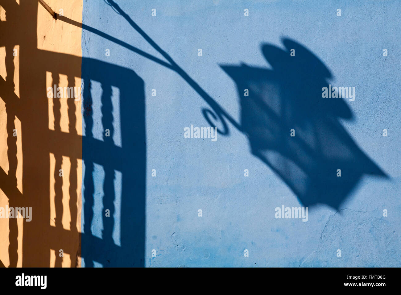 Shadows of spindles of window shutter and lantern on wall at Trinidad ...