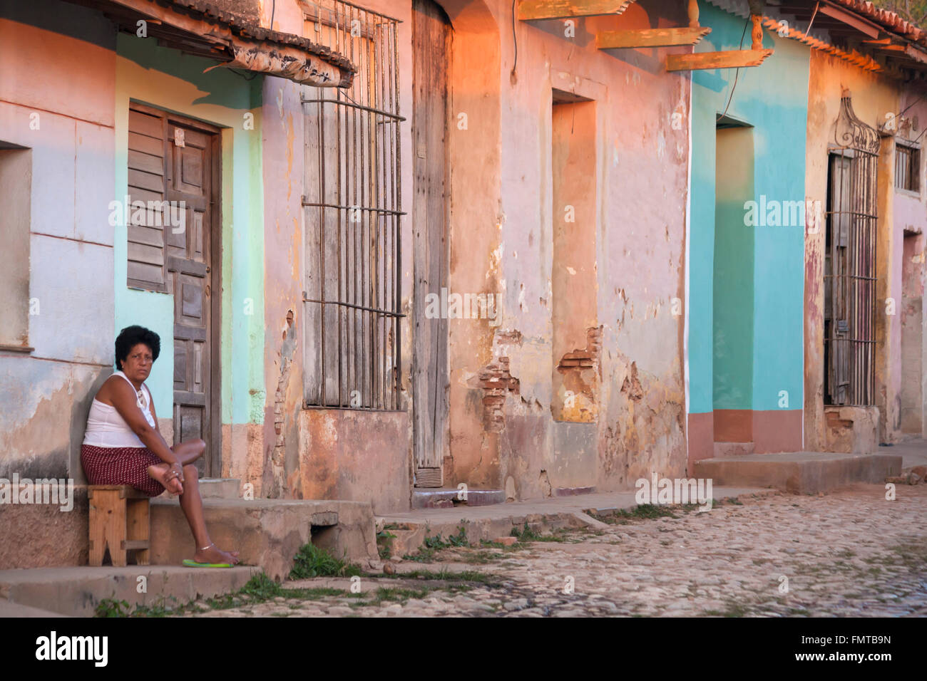 Daily life in Cuba - Cuban woman sat on stool in street outside houses ...