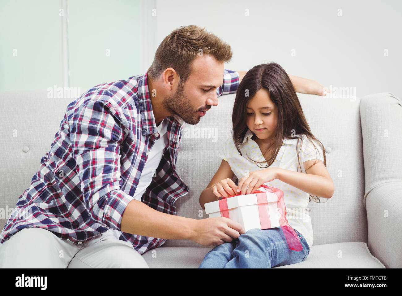 Father helping girl in tying gift box Stock Photo - Alamy