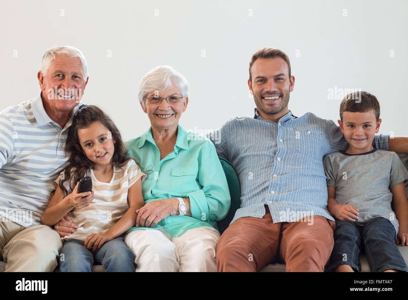 Happy family sitting on sofa Stock Photo - Alamy