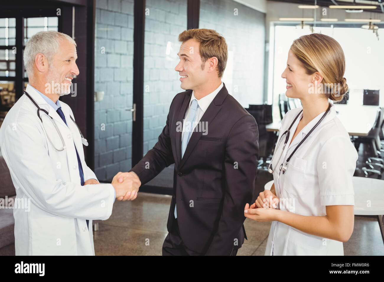 Two confident doctors shaking hands with each other Stock Photo - Alamy