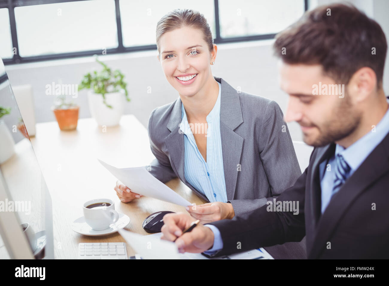 Businesswoman sitting beside male colleague at computer desk Stock ...