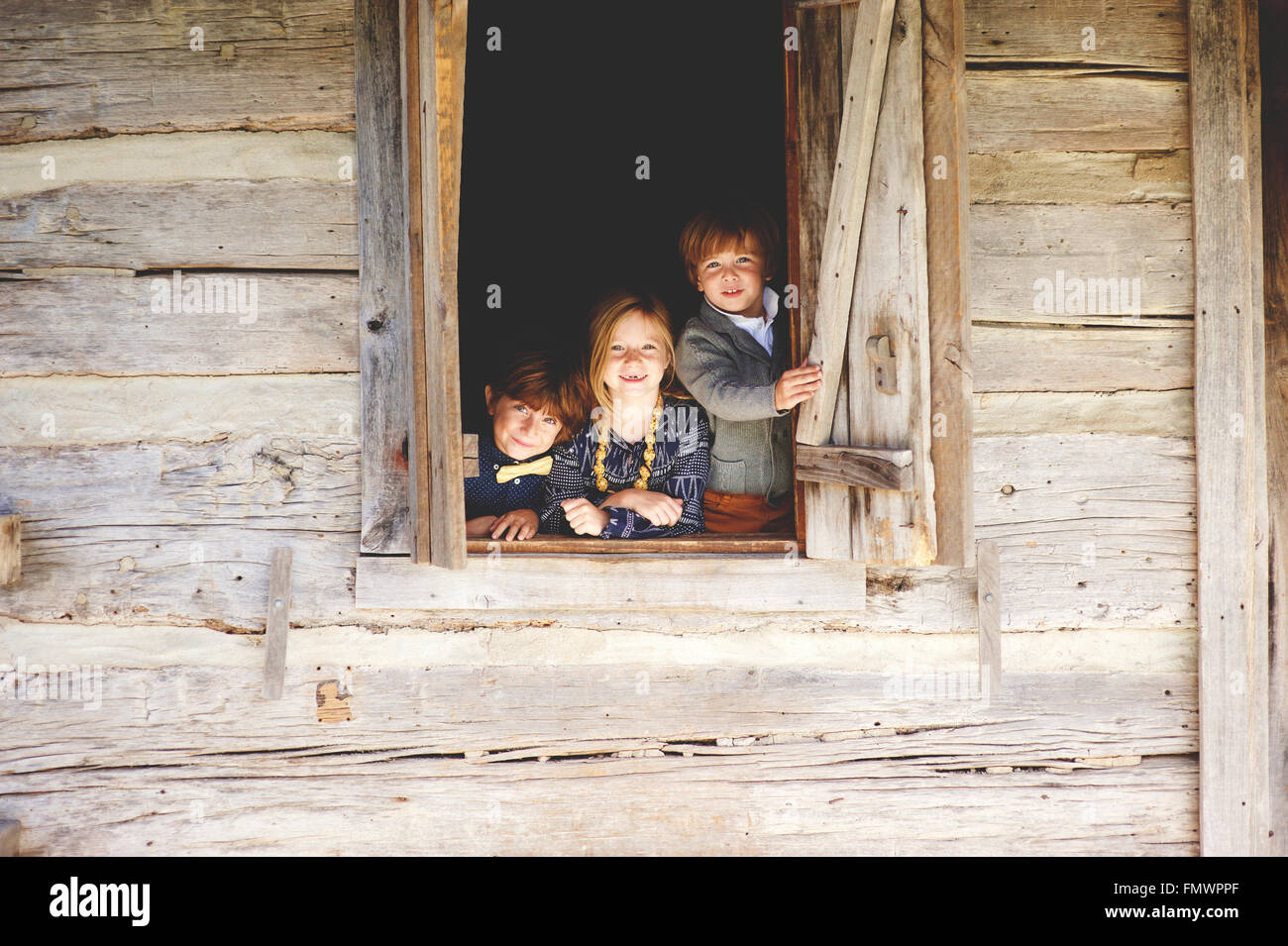 Three kids peeking out a window Stock Photo - Alamy