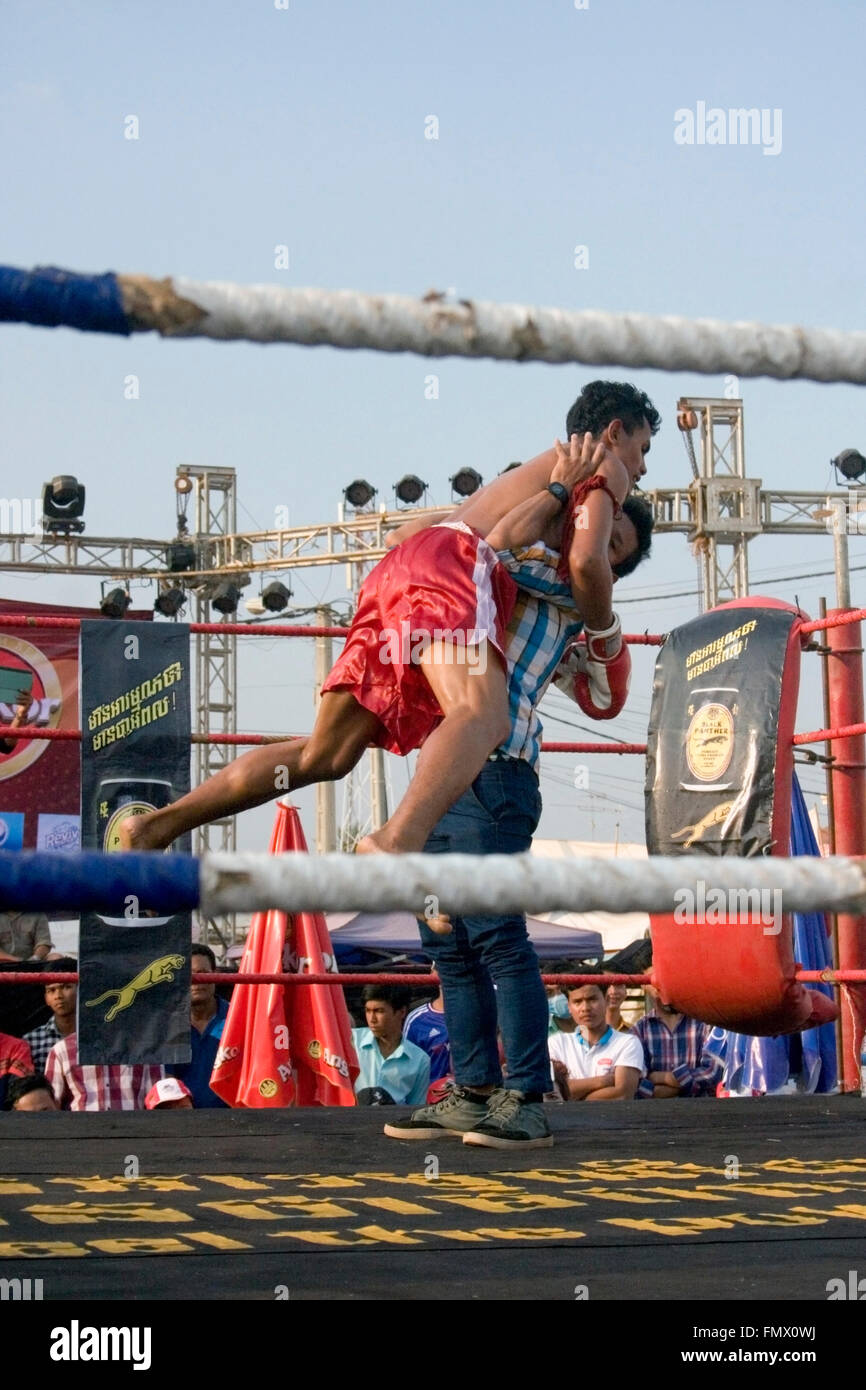 A Muay Thai boxer is lifted off the canvas by a cornerman in a boxing ...