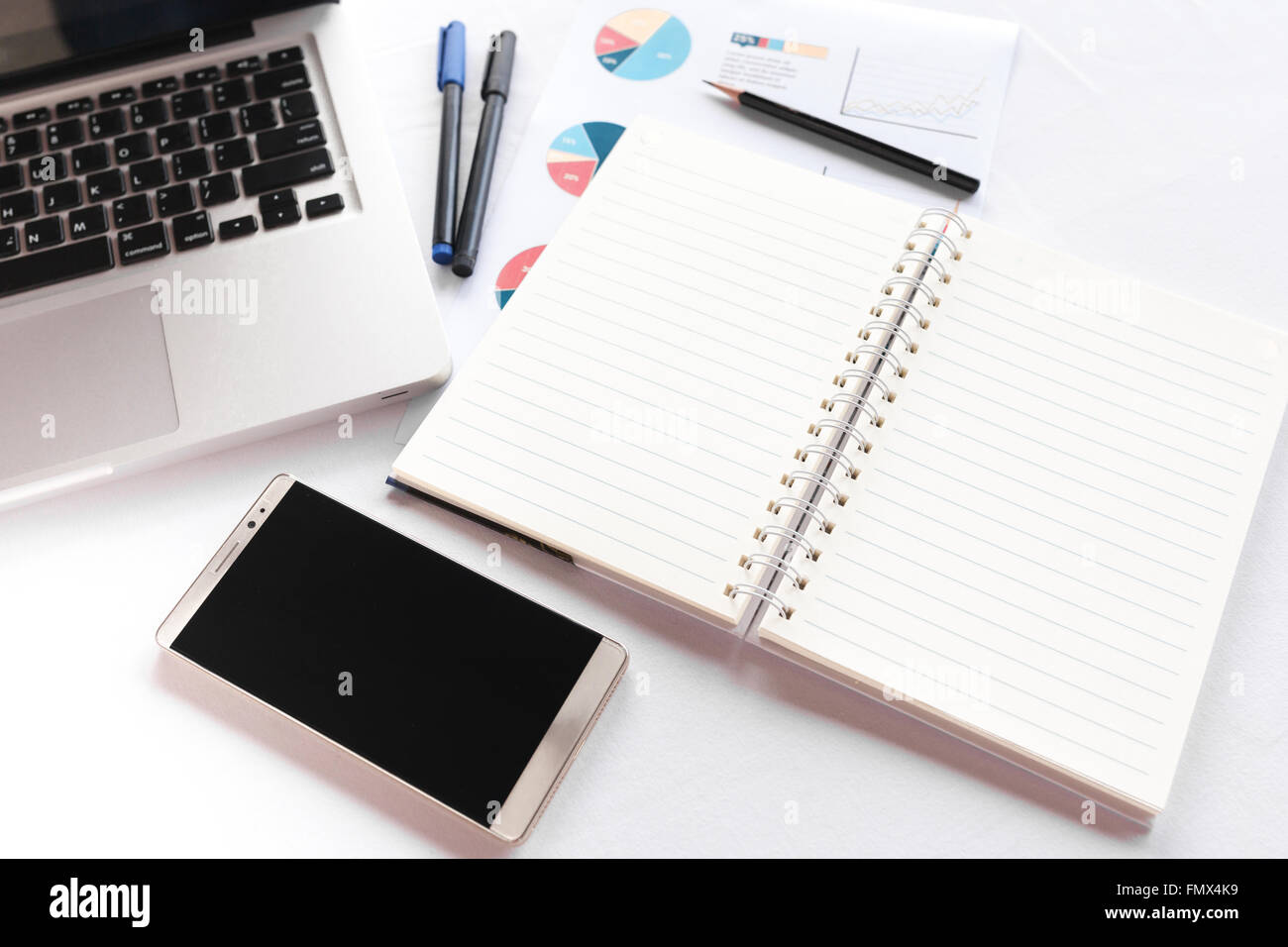 Blank note book with pencil pen laptop and smartphone on white table ...