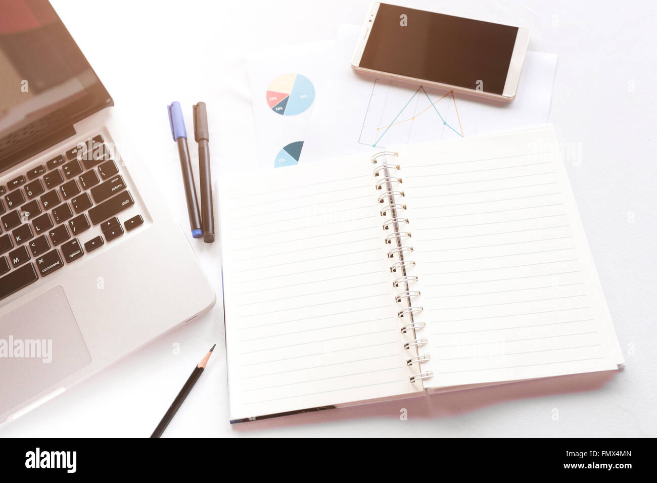 Blank note book with pencil pen laptop and smartphone on white table ...