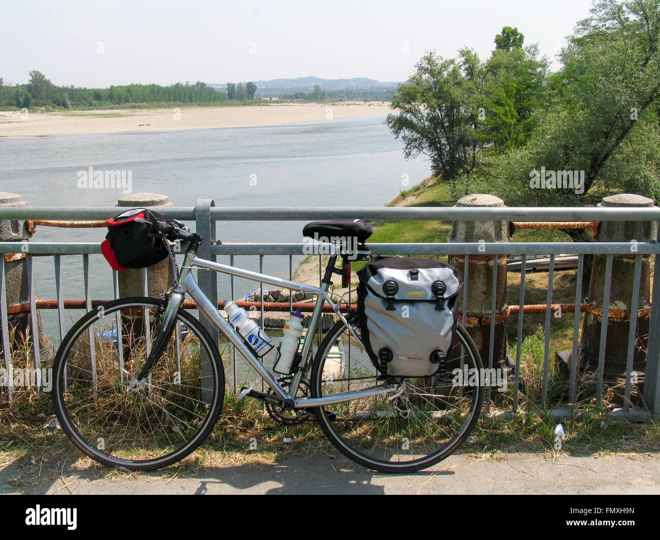 A touring bicycle leaning against the railing of a bridge crossing the ...