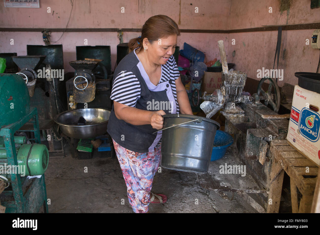 A Filipino lady making peanut butter and a delicacy called Babinka with ...