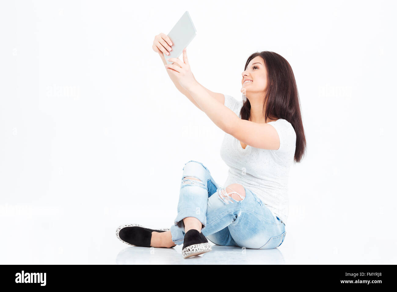 Smiling casual woman making selfie photo on tablet computer isolated on ...