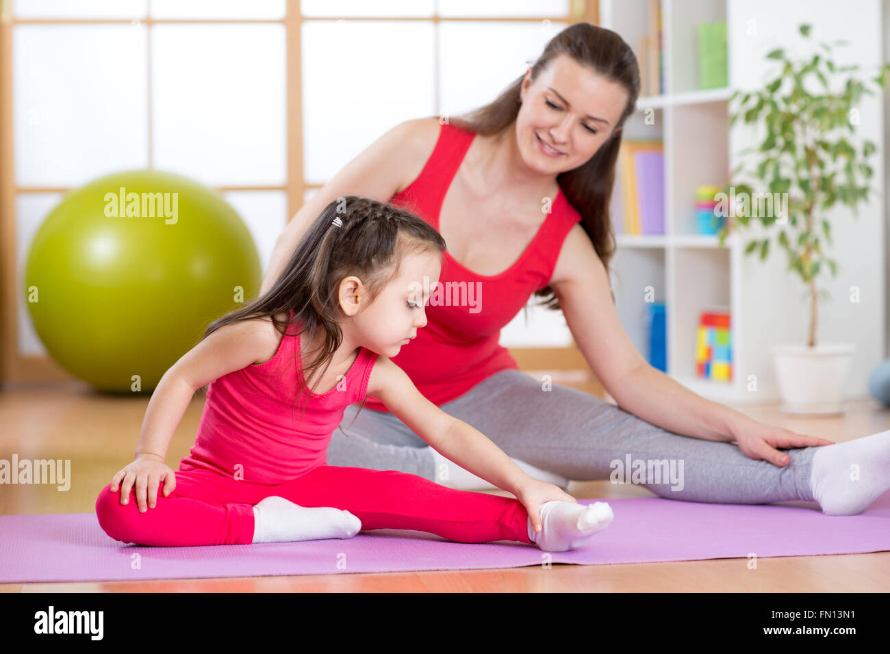 Mother and daughter doing fitness exercises on mat at home Stock Photo ...