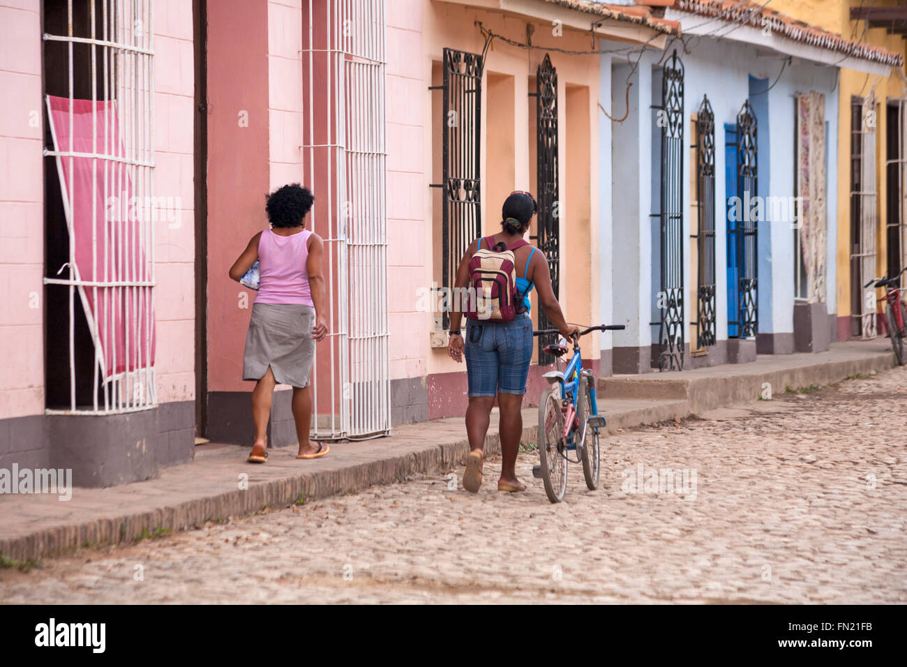 Daily life in Cuba - two Cuban woman walking down cobbled street, one ...