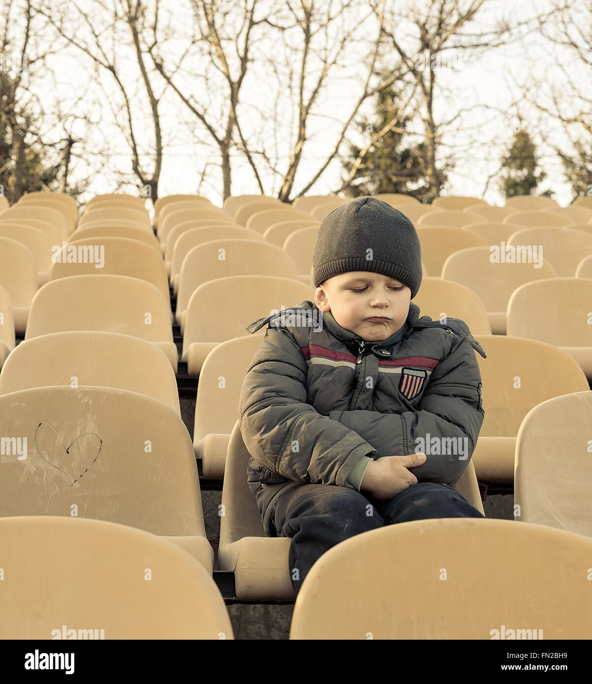 A little boy sits on a stadium bench and sad Stock Photo - Alamy