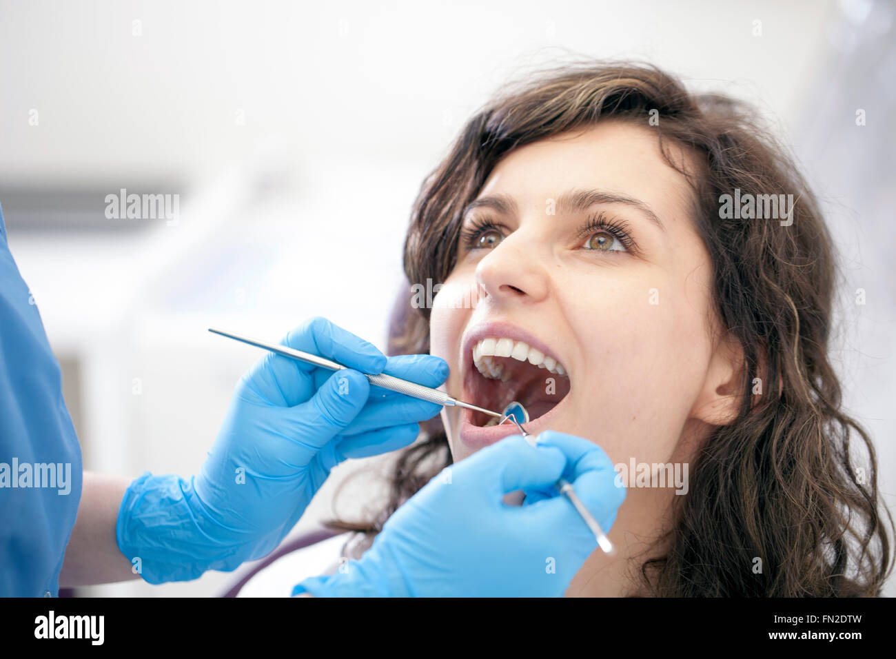 Beautiful patient in the dental chair. The doctor examines her teeth ...