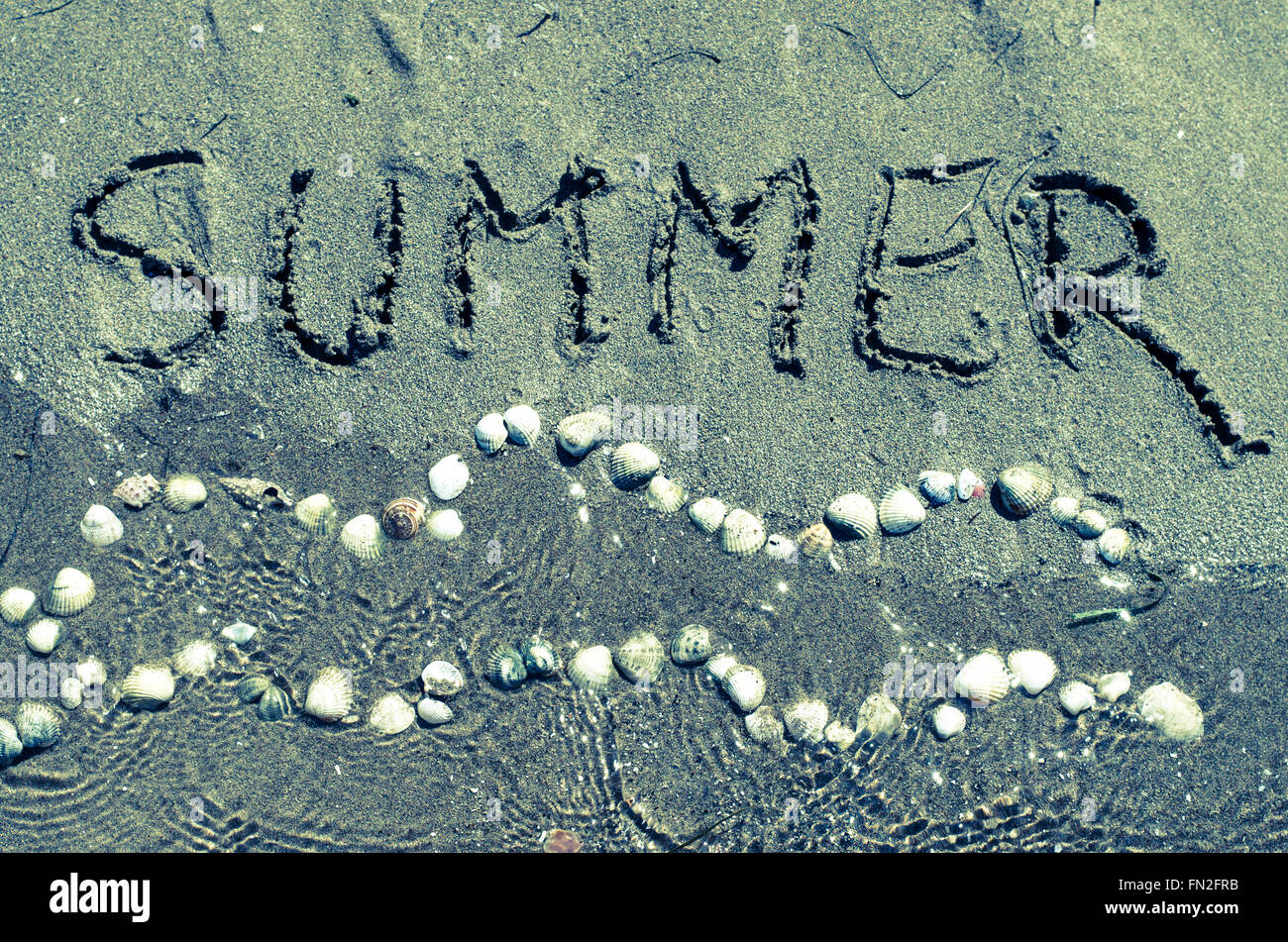 waves from shells and summer word on sand on beach Stock Photo - Alamy