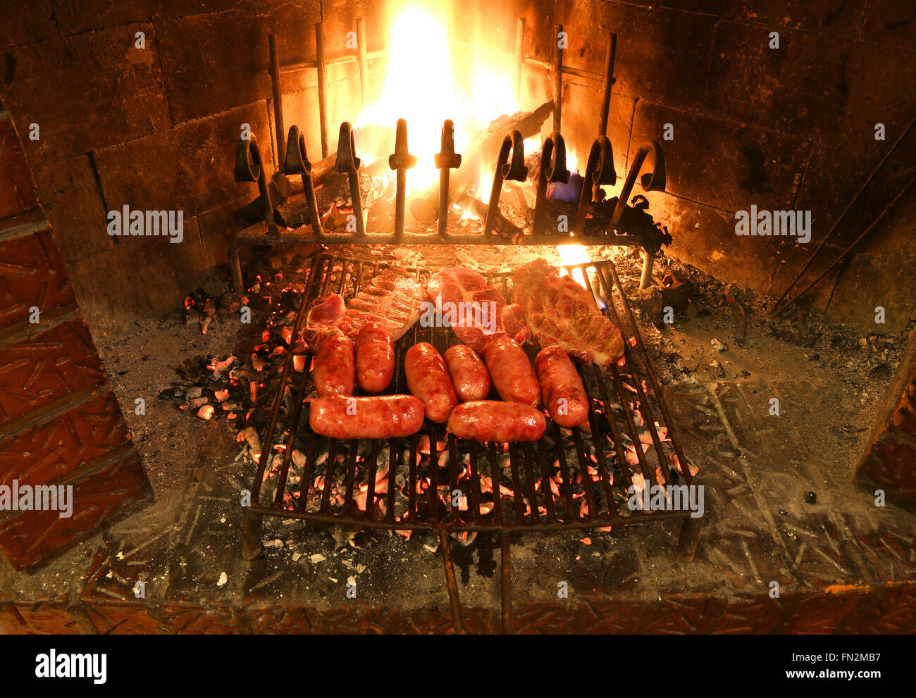 pork sausages and meat cooking in the grill of the fireplace Stock ...