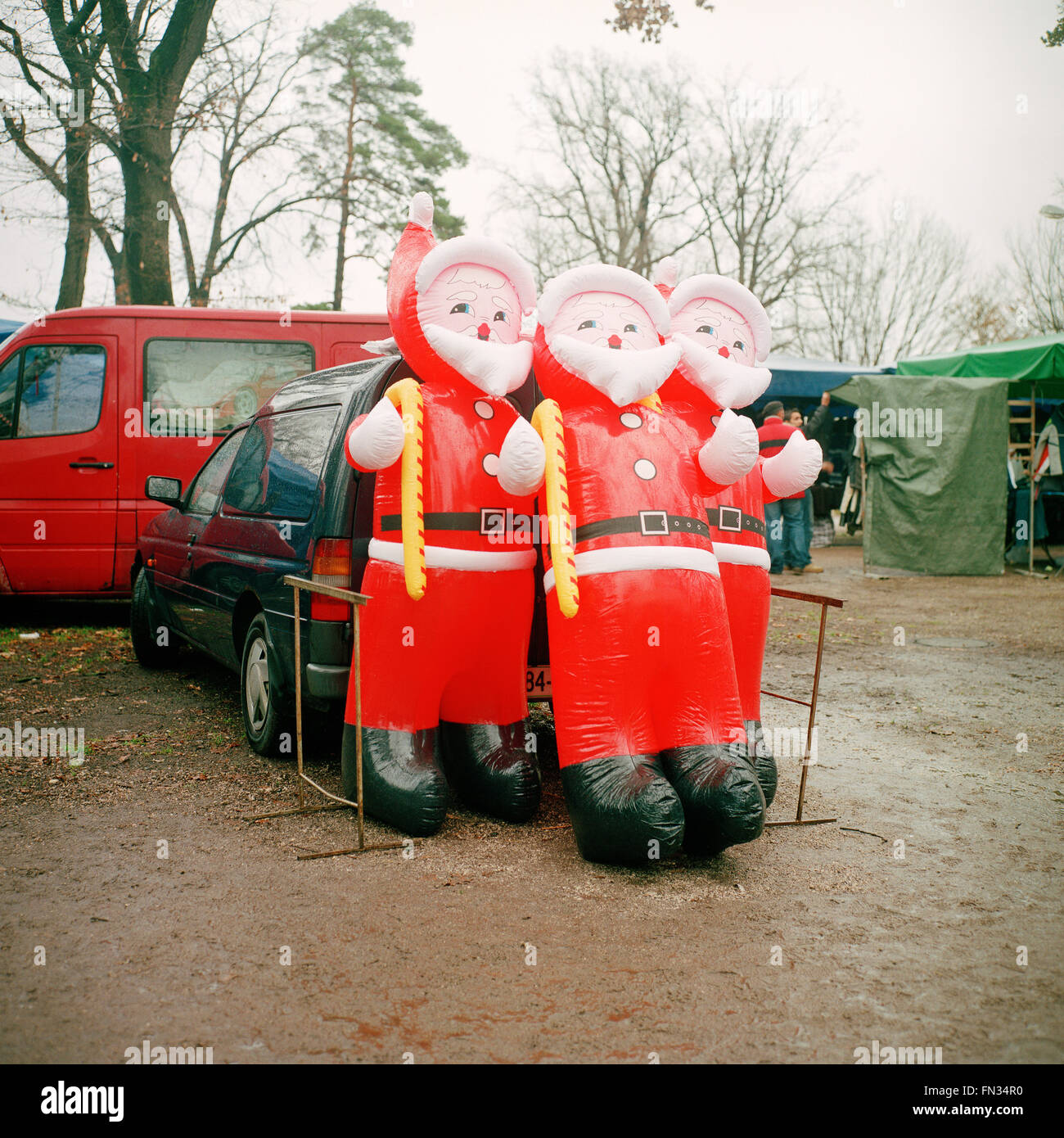 Three inflatable plastic Santas standing in the mud at Christmas time ...