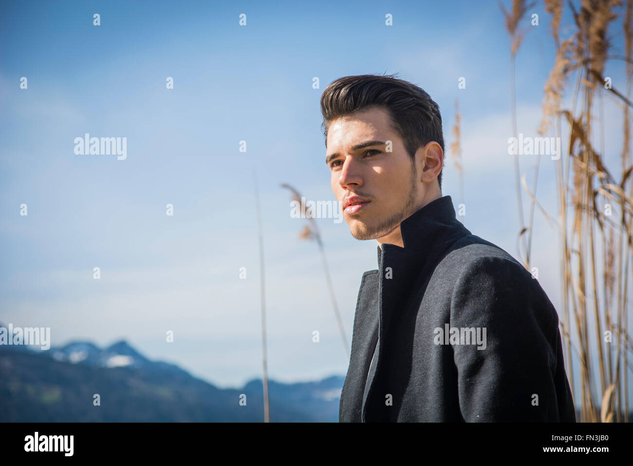 Handsome young man on Luzern lake's shore in a sunny, peaceful day ...