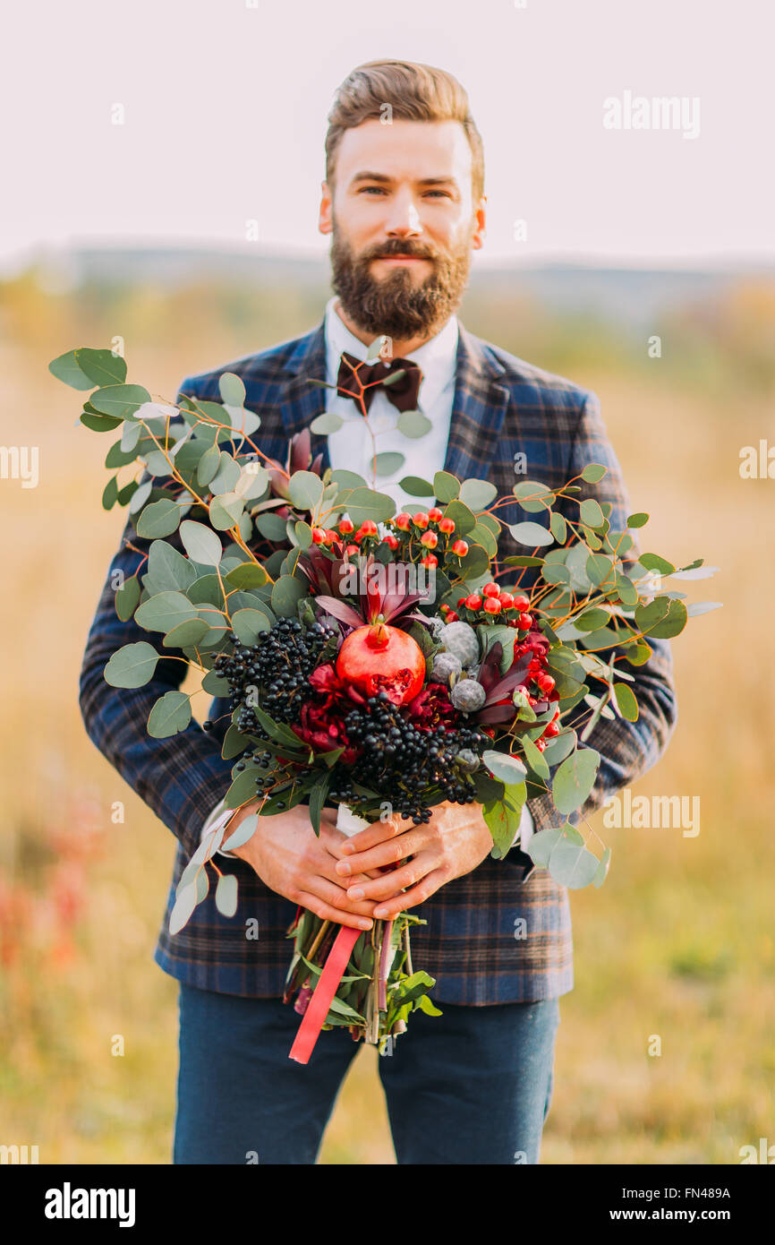 Bearded groom with bouquet of fruits on the field Stock Photo - Alamy