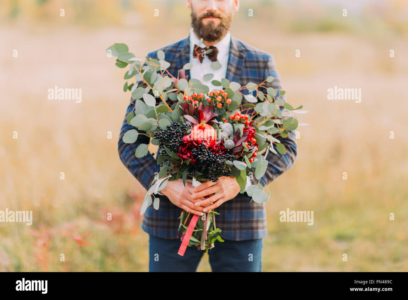 Bearded groom with bouquet of fruits on the field Stock Photo - Alamy