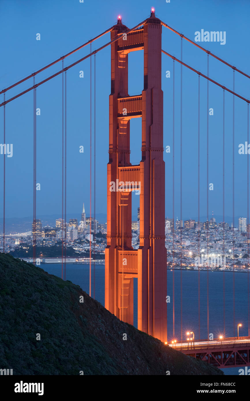 The north tower of the Golden Gate Bridge at night with the city of San ...