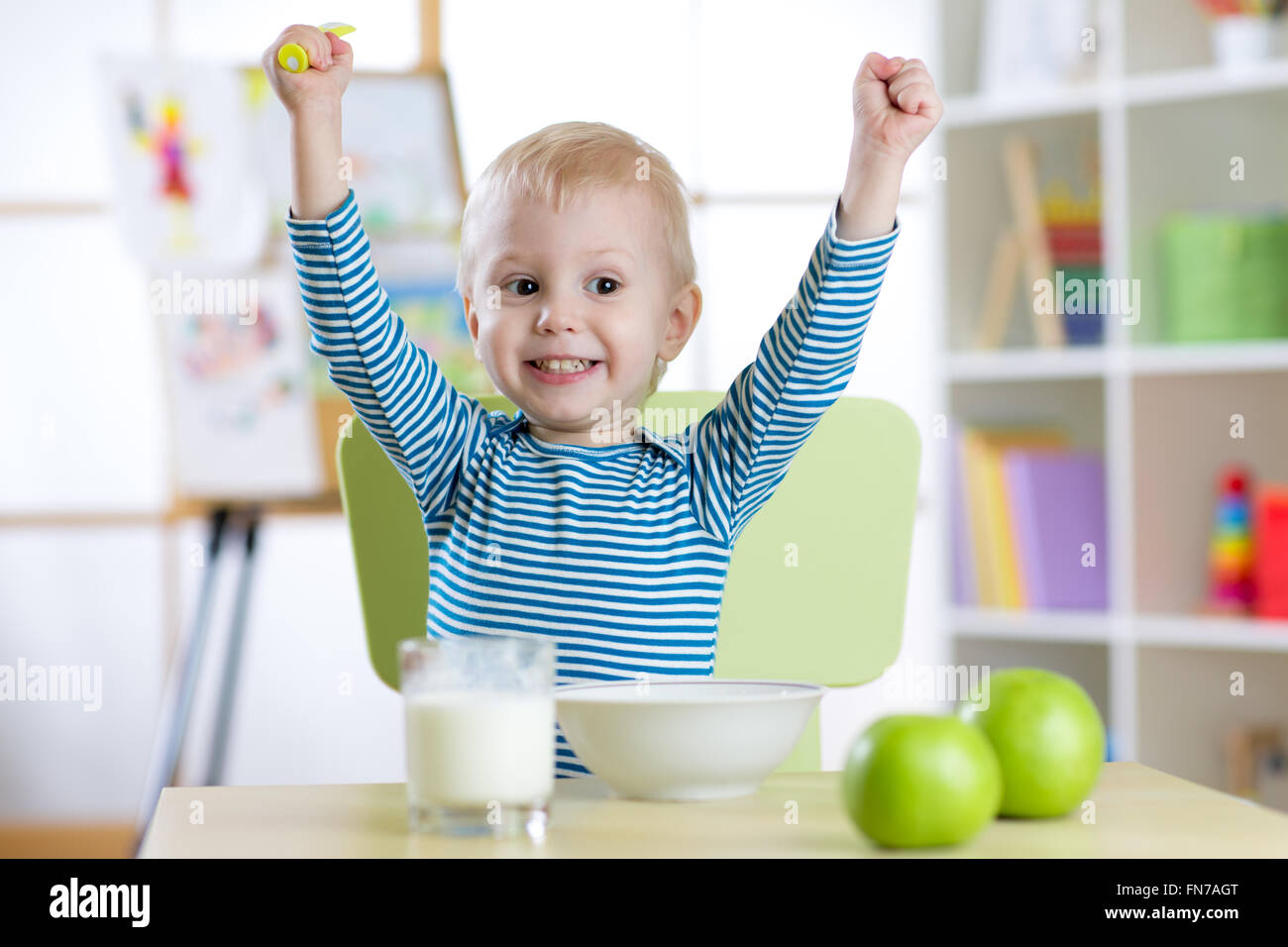 Happy child boy eating breakfast with hands up Stock Photo - Alamy