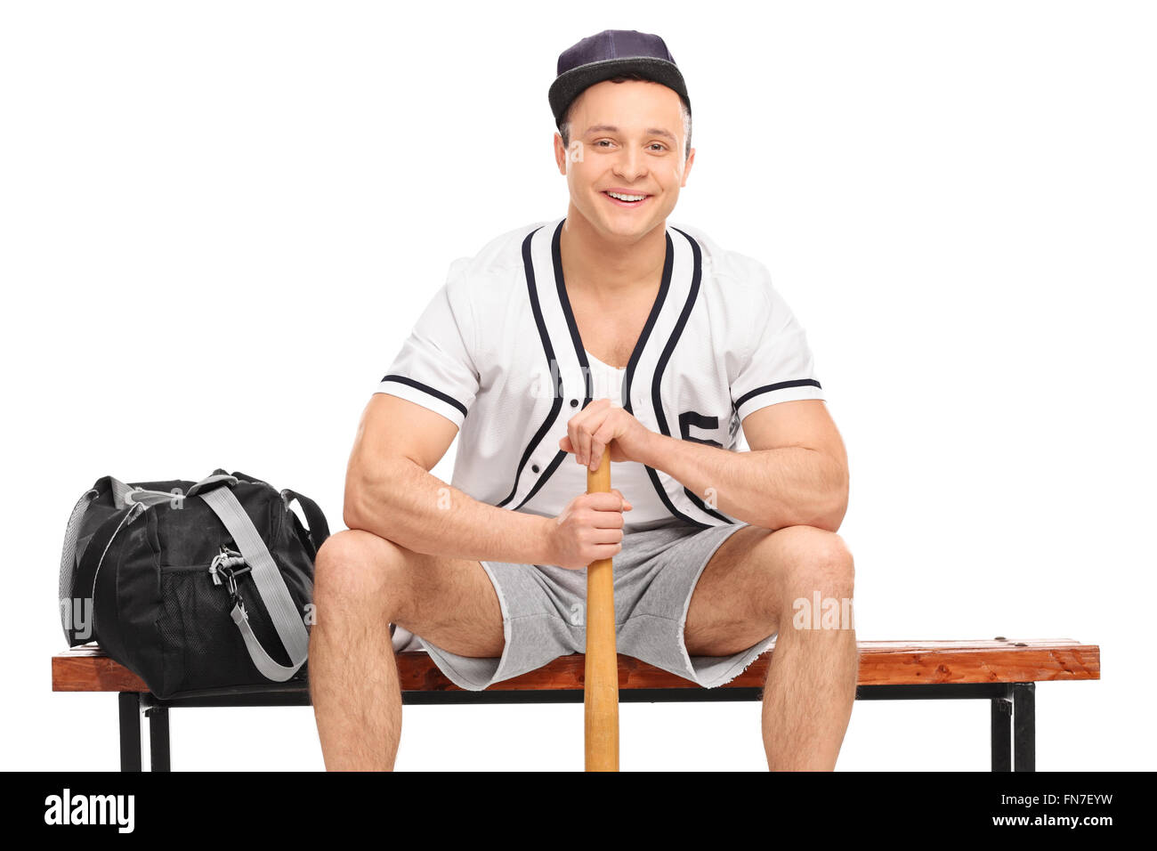 Young baseball player sitting on a bench and holding a baseball bat ...