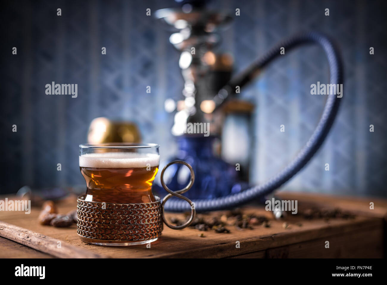 Black tea in glass cup on wooden table, hookah in background Stock ...