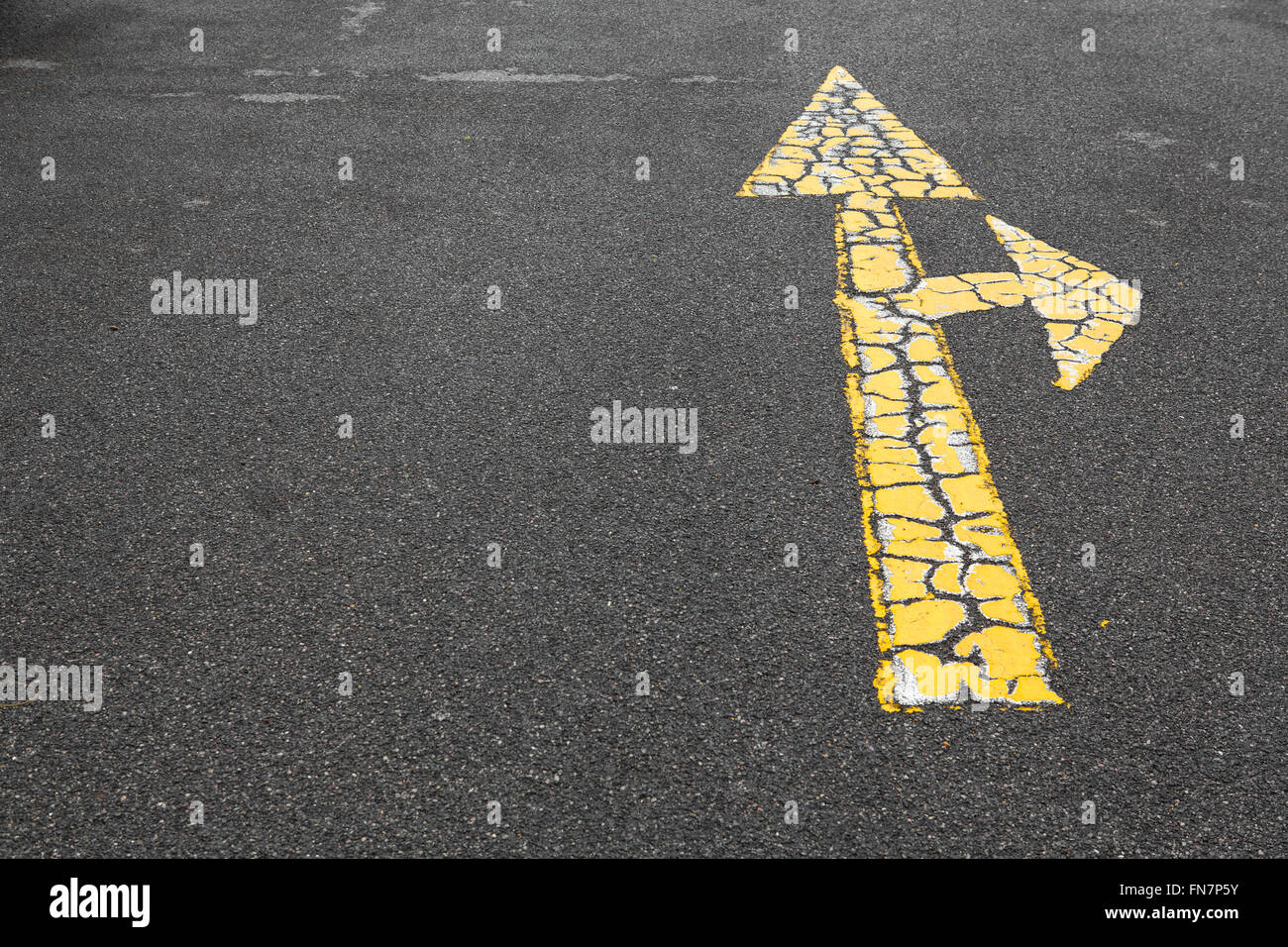 An old painted and faded arrow sign on the tarmac of a road indicating ...