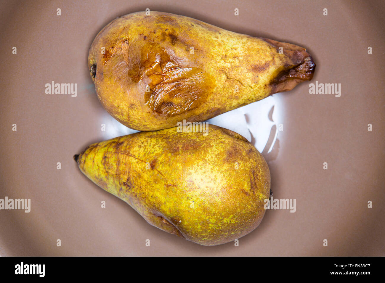 A small bowl of fruit in a home with 2 pears that are going soft and ...