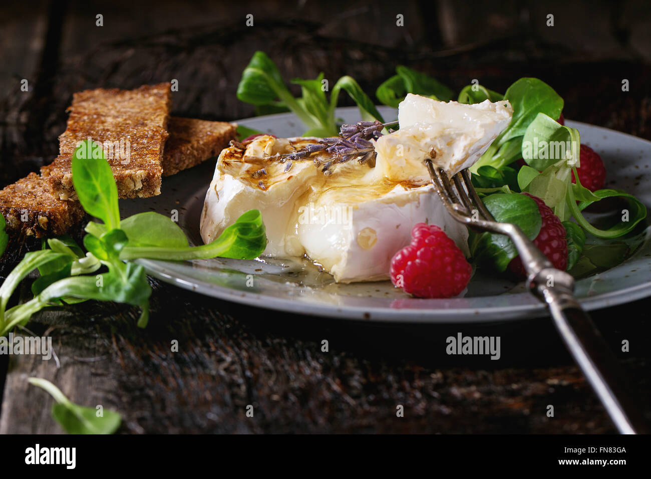 Baked Goat cheese with honey and raspberries Stock Photo - Alamy