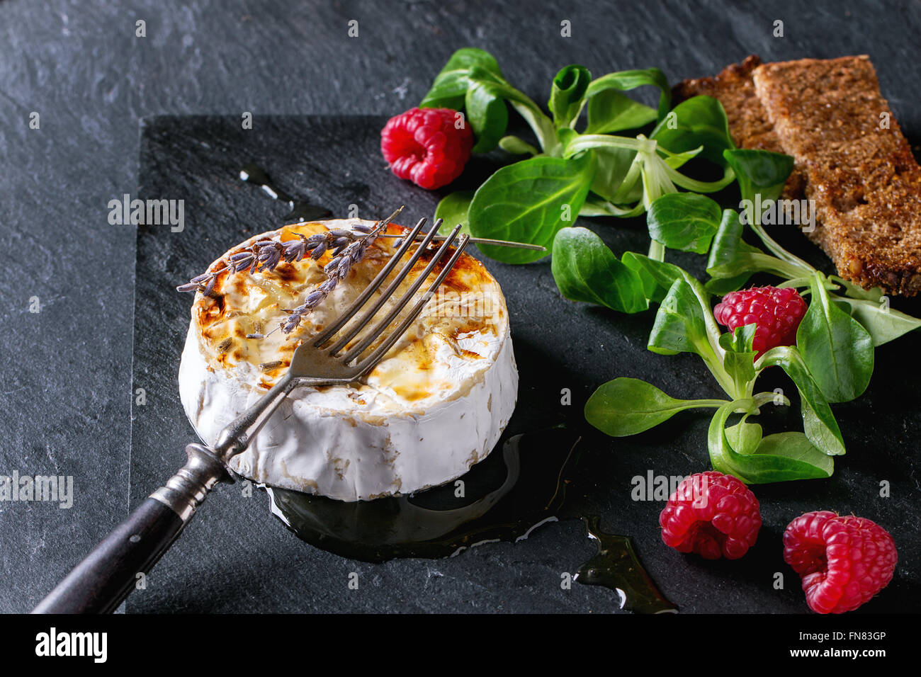 Baked Goat cheese with honey and raspberries Stock Photo - Alamy
