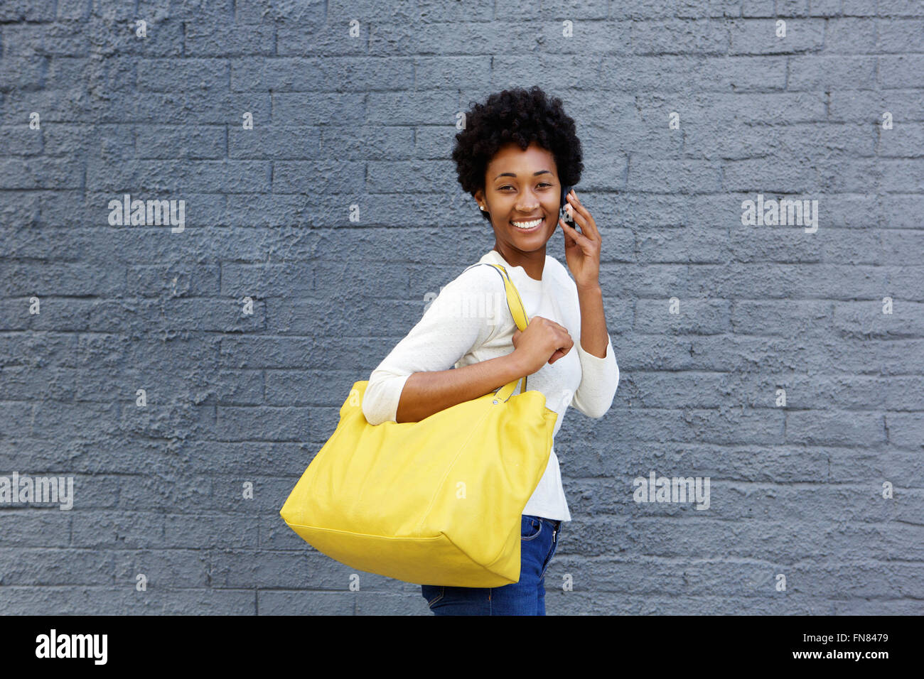 Portrait of an attractive young woman with bag walking and talking on ...