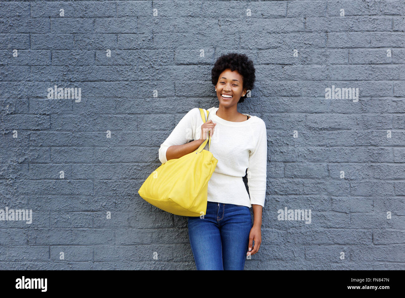 Portrait of a beautiful young african woman with handbag standing ...