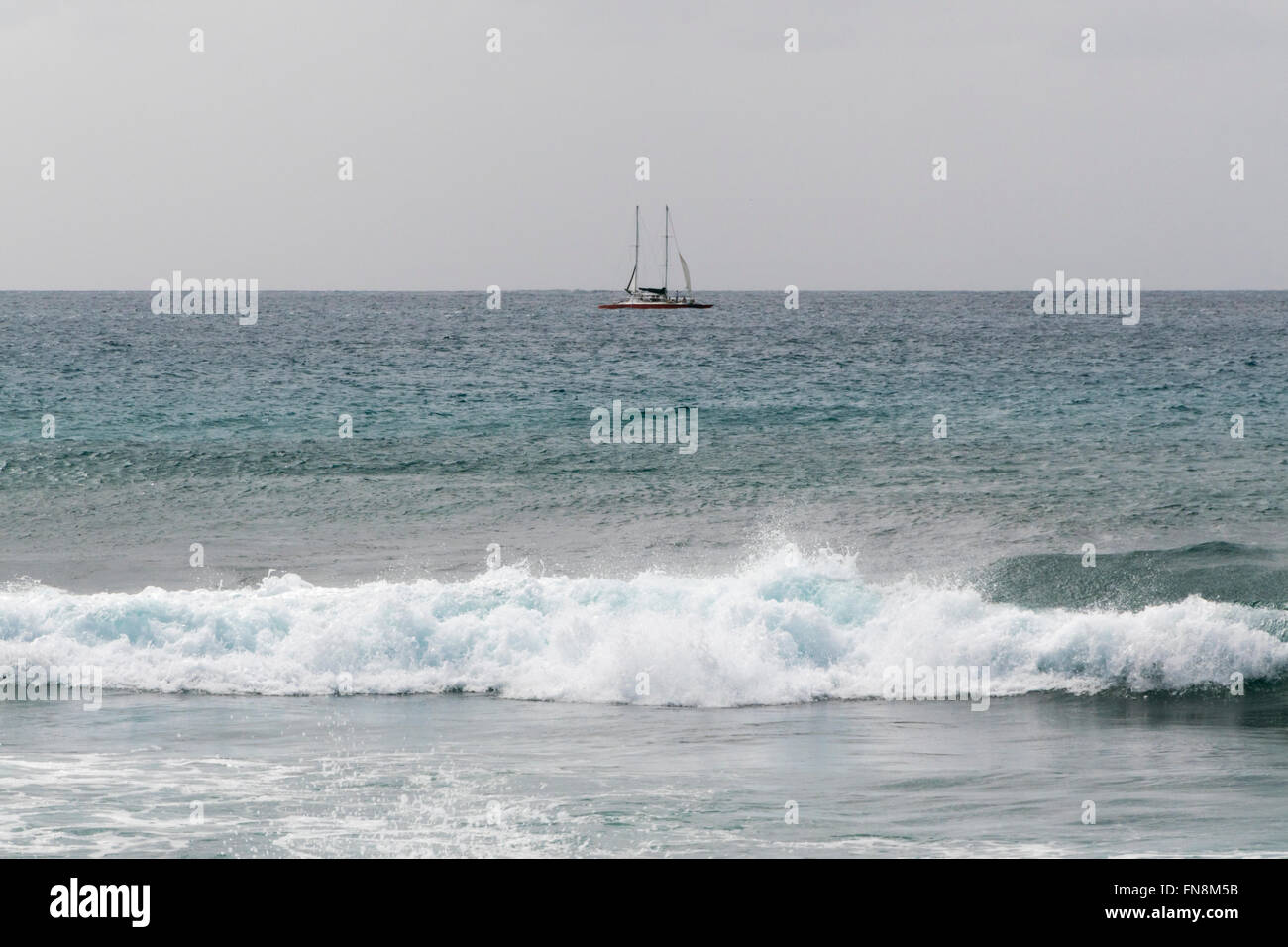 Waves breaking on the shore with a boat in the distance at sea Stock ...