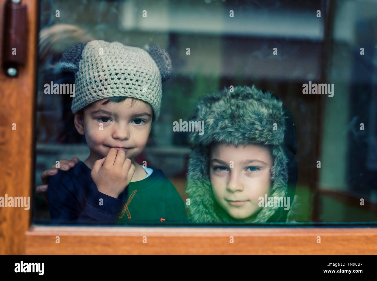 Two boys looking out of a window Stock Photo - Alamy