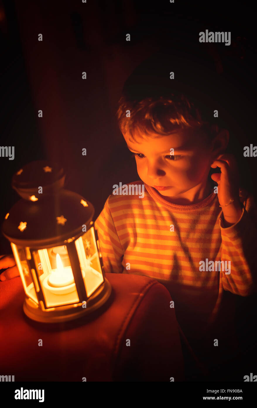 Boy looking at night candle Stock Photo - Alamy