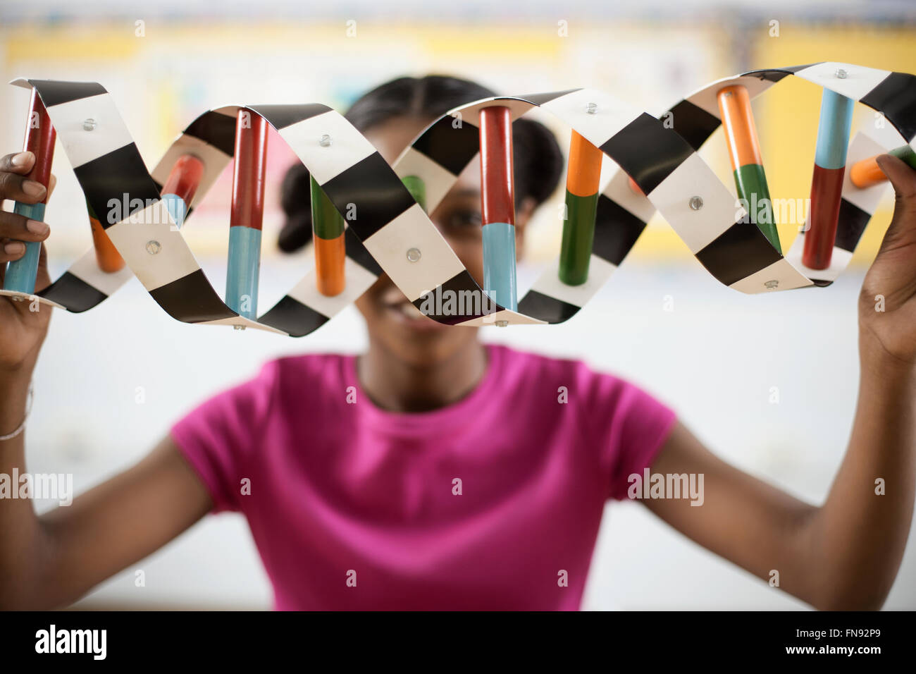 A girl in a science class holding a model of a helix structure in front ...