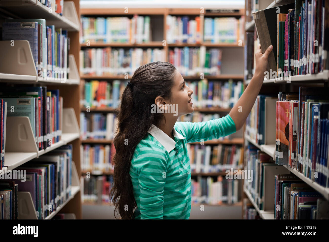 A girl looking at books in a library Stock Photo - Alamy
