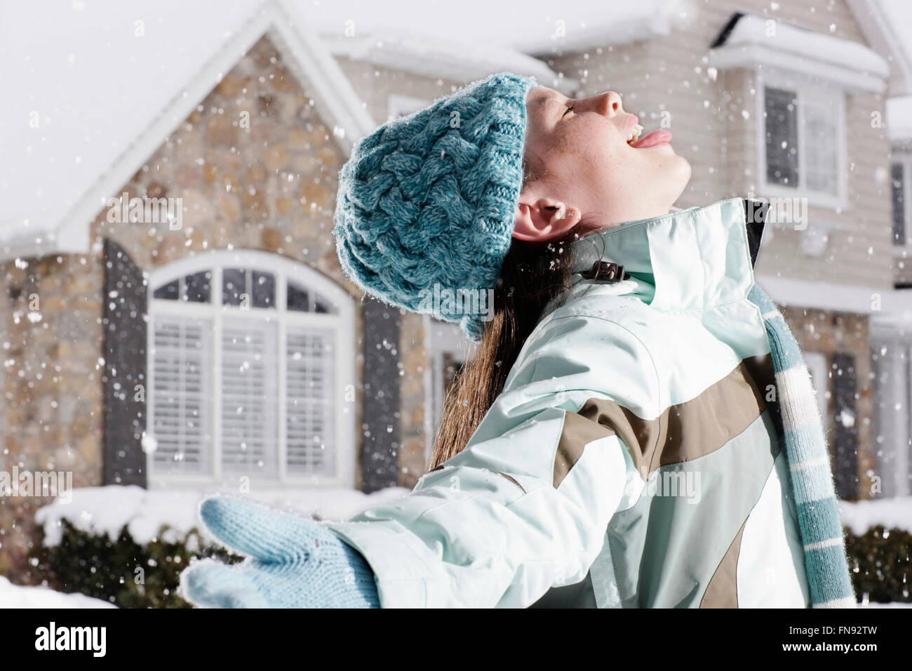 Winter snow. A girl holding out her arms with her head back, catching ...