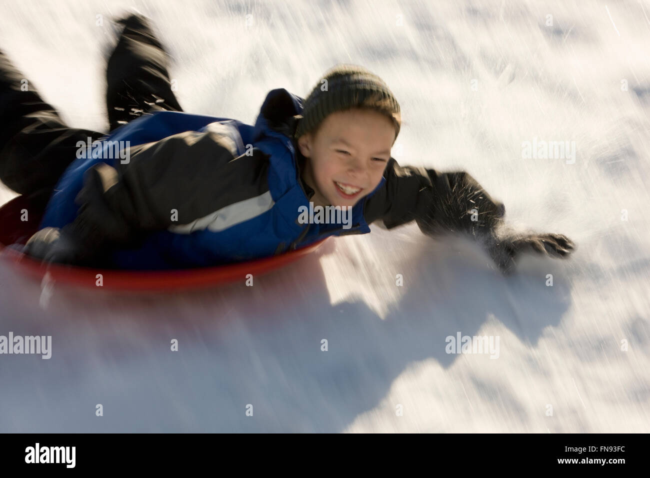 A boy lying on a sledge in the snow Stock Photo - Alamy