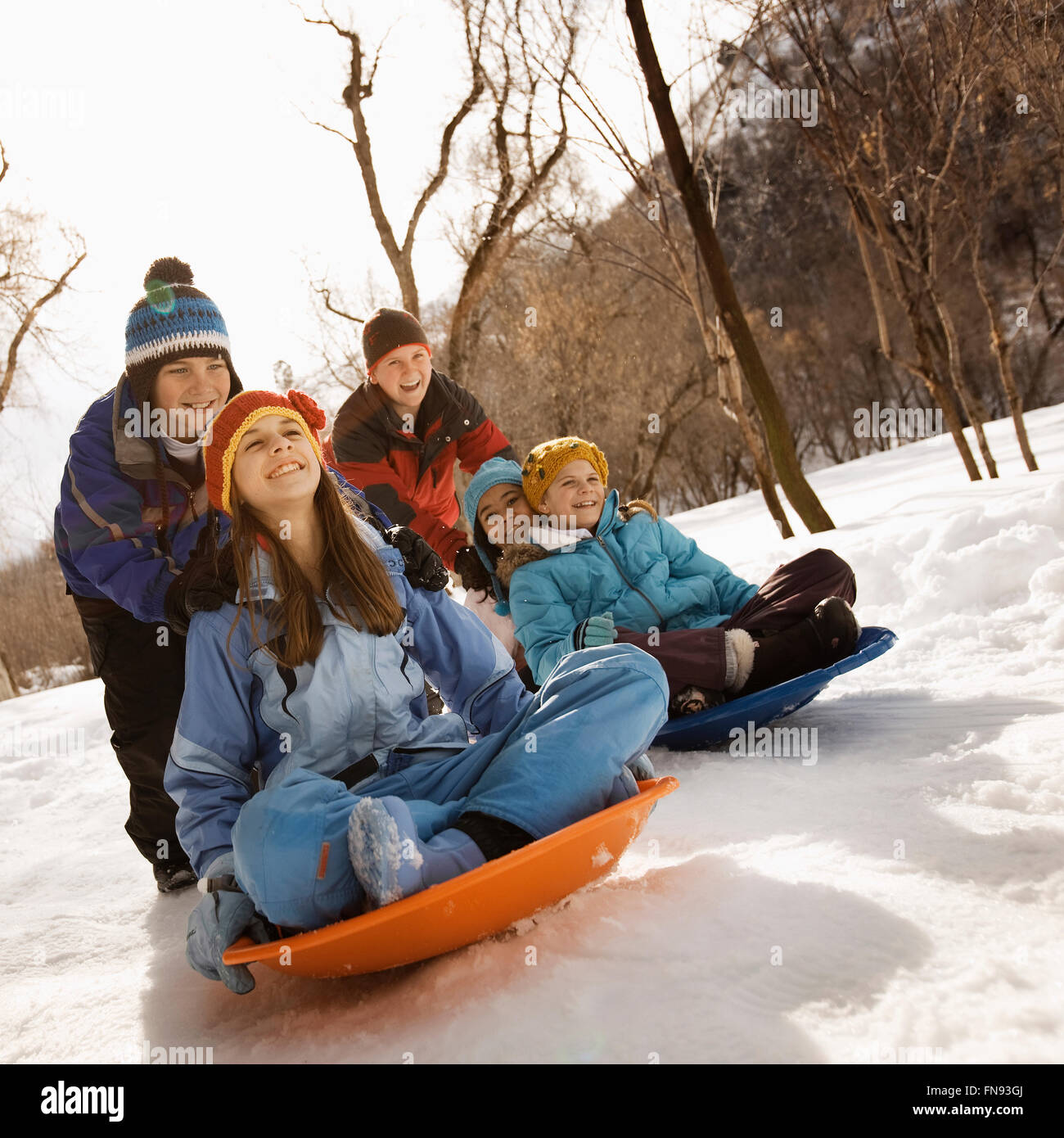 A group of children, boys and girls, riding on sledges on the snow ...