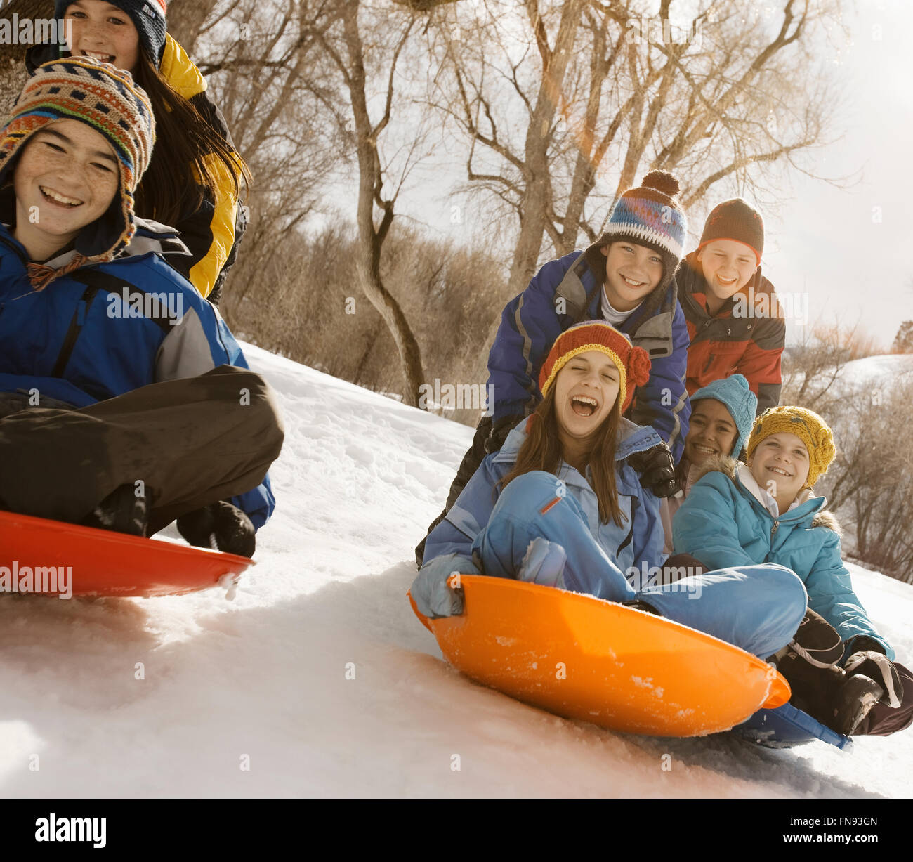 A group of children, boys and girls, riding on sledges on the snow ...