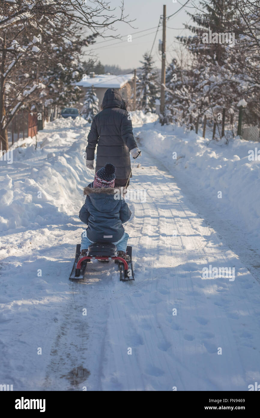 Woman pulling a sledge with her daughter Stock Photo - Alamy