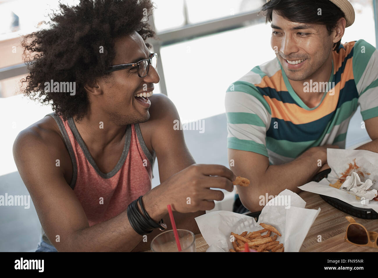 Two young men sitting eating at a diner Stock Photo - Alamy