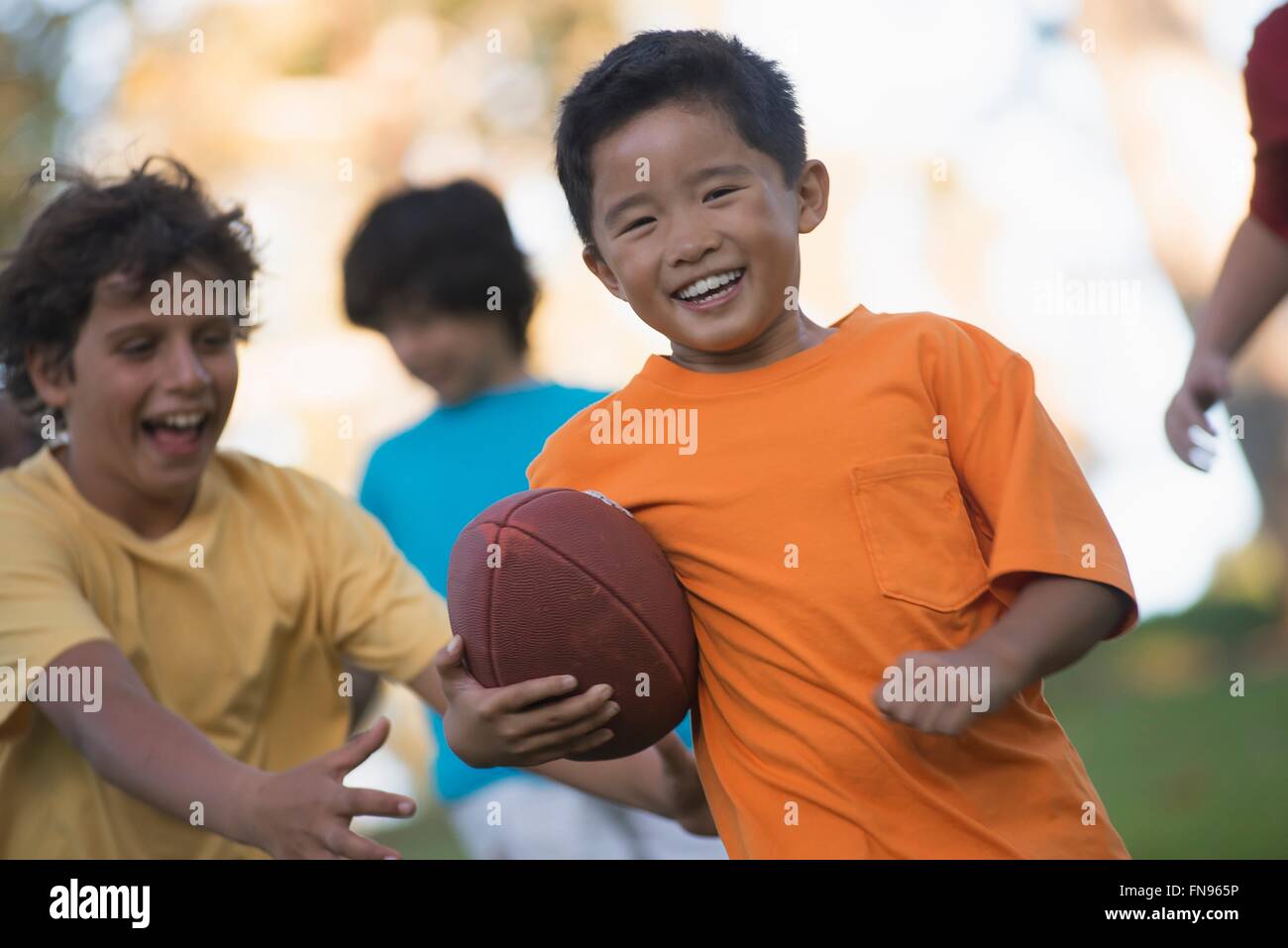 Children playing outdoors in summer, one running with a ball Stock ...